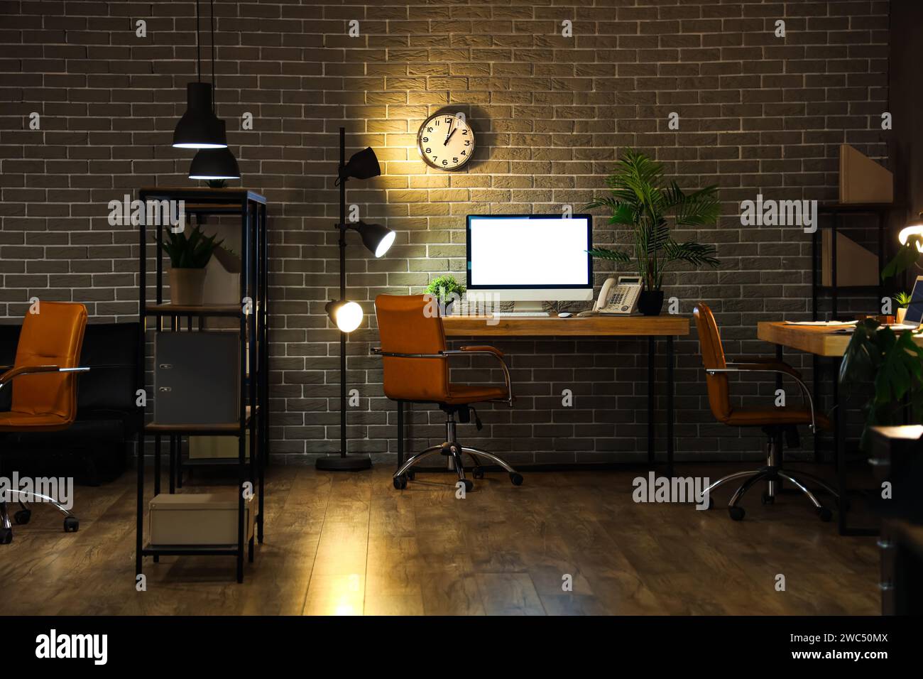 Interior of dark office with desks, shelf unit and glowing lamps at ...