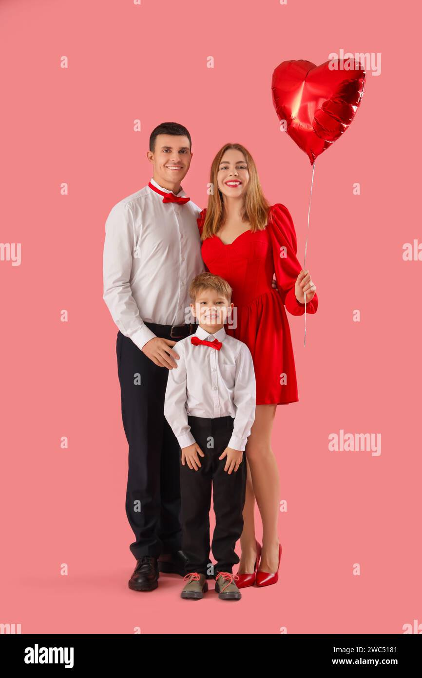 Little boy with his parents and heart-shaped balloon on pink background ...