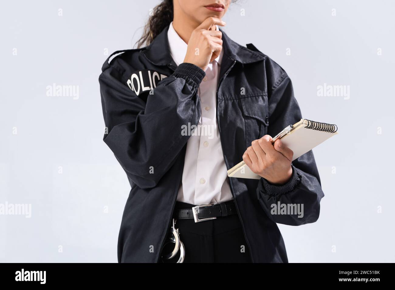 Thoughtful African-American female police officer with notebook on ...