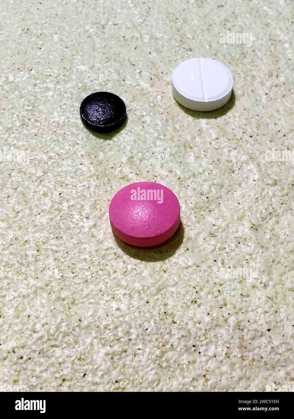 White, black and pink medical pill on a beige ceramic plate. Concept of ...
