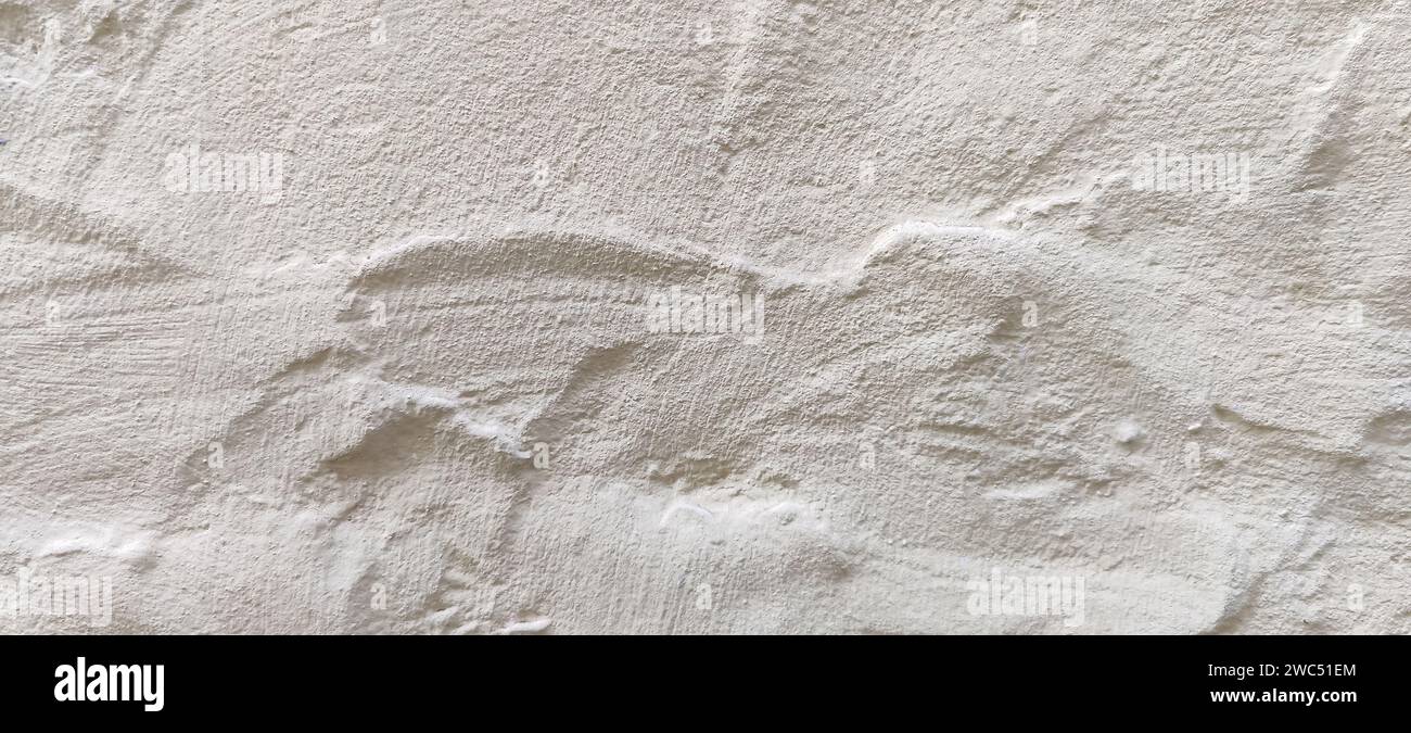 The rough texture of a poorly plastered light-colored wall. An uneven ...