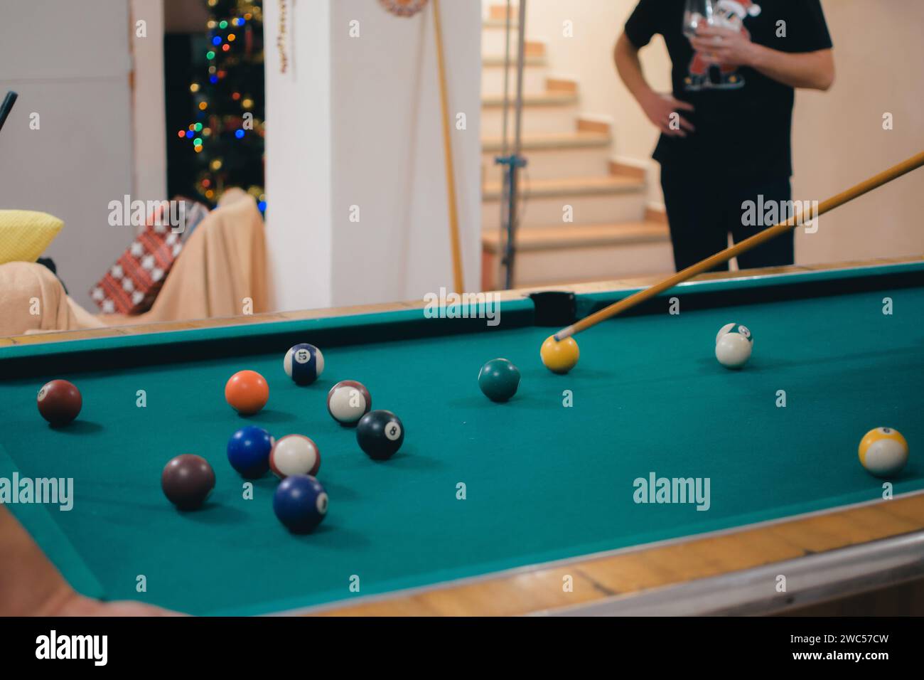 A skilled man holds a pool stick confidently, poised to strike the cue ...