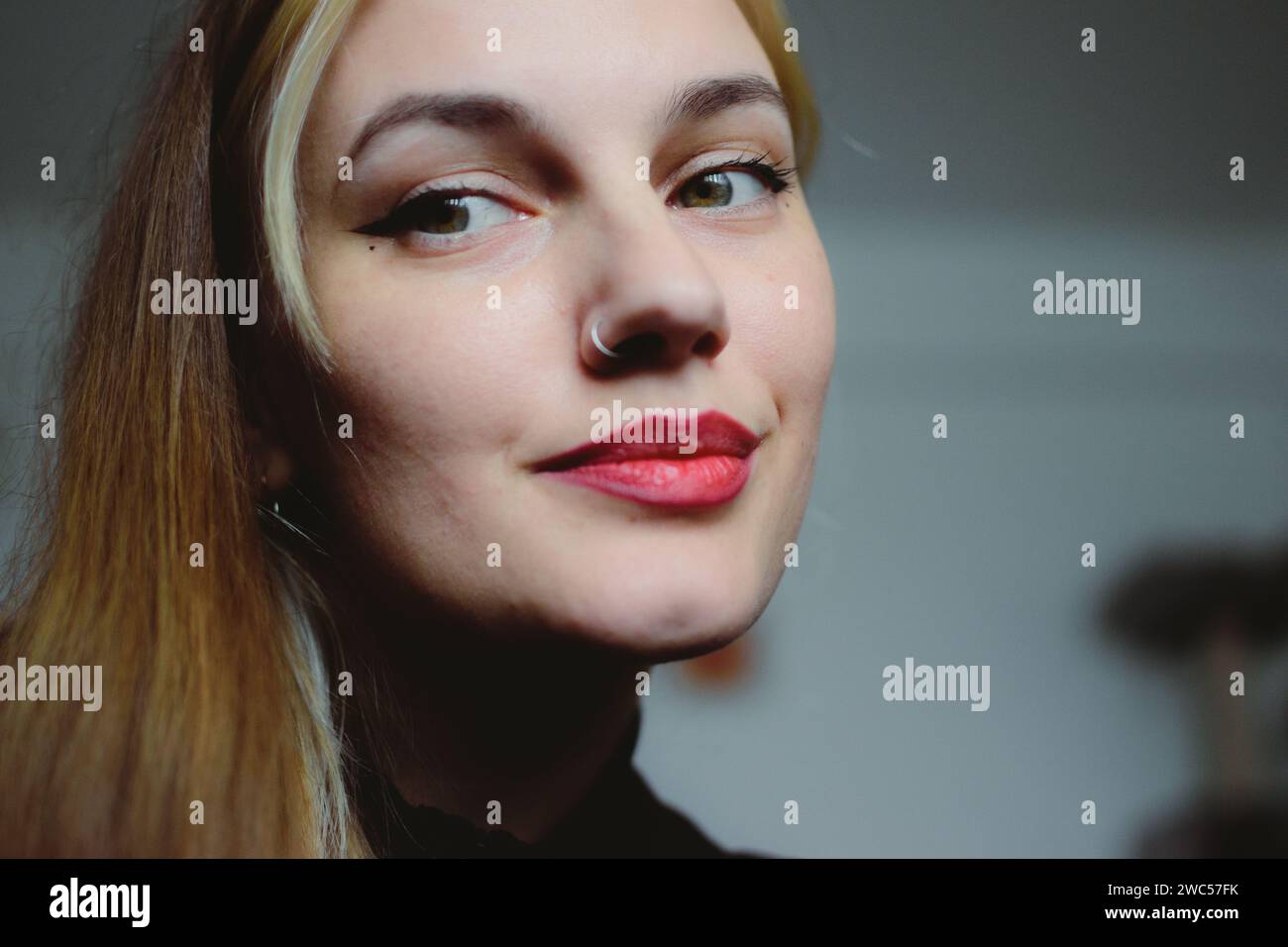 A young woman with a bold red lipstick is facing the camera with a ...