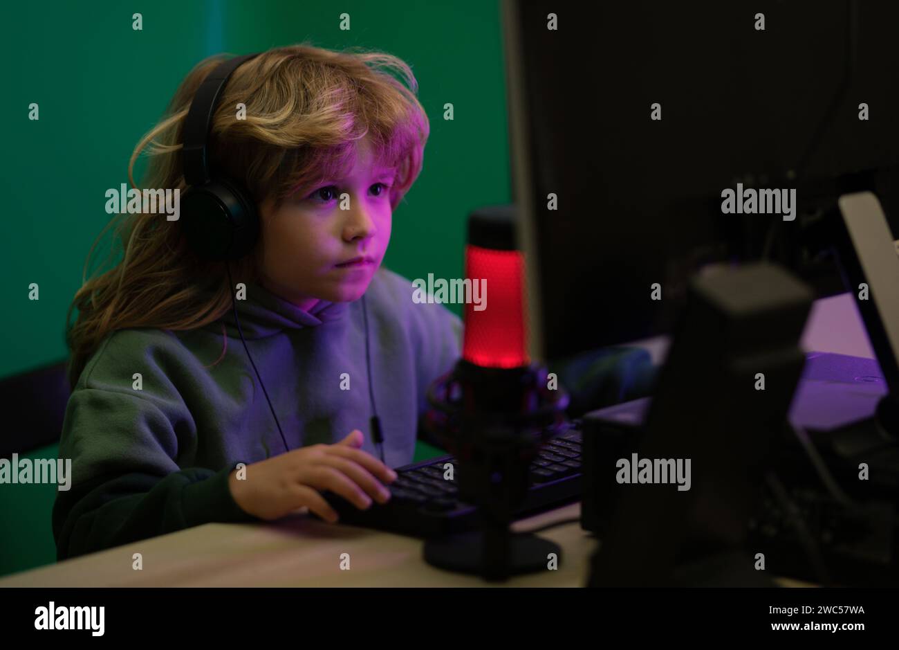 Kid using pc at night. Child with computer in a dark room. A little boy ...