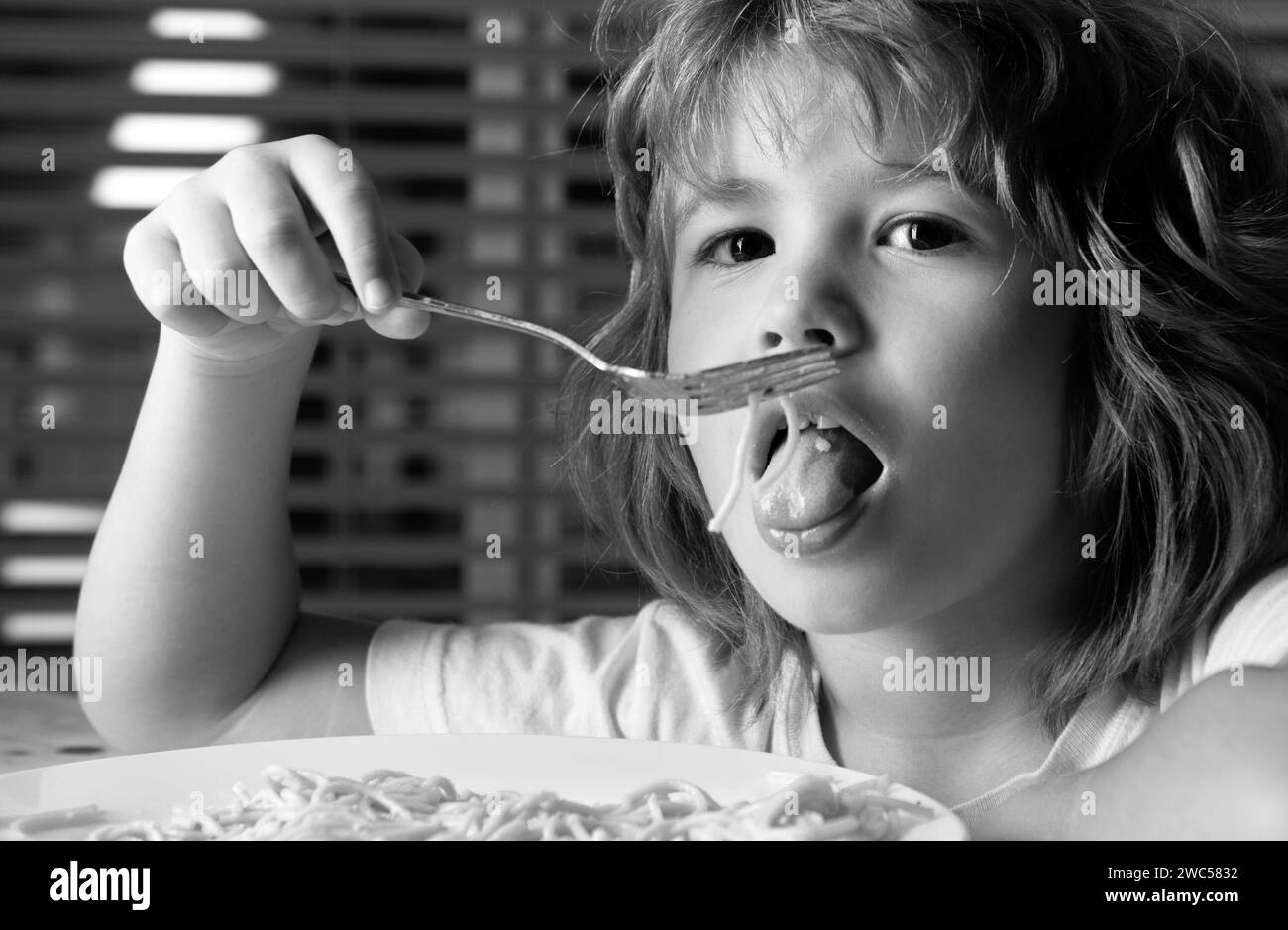 Close up portrait of a cute little child eating pasta, spaghetti ...