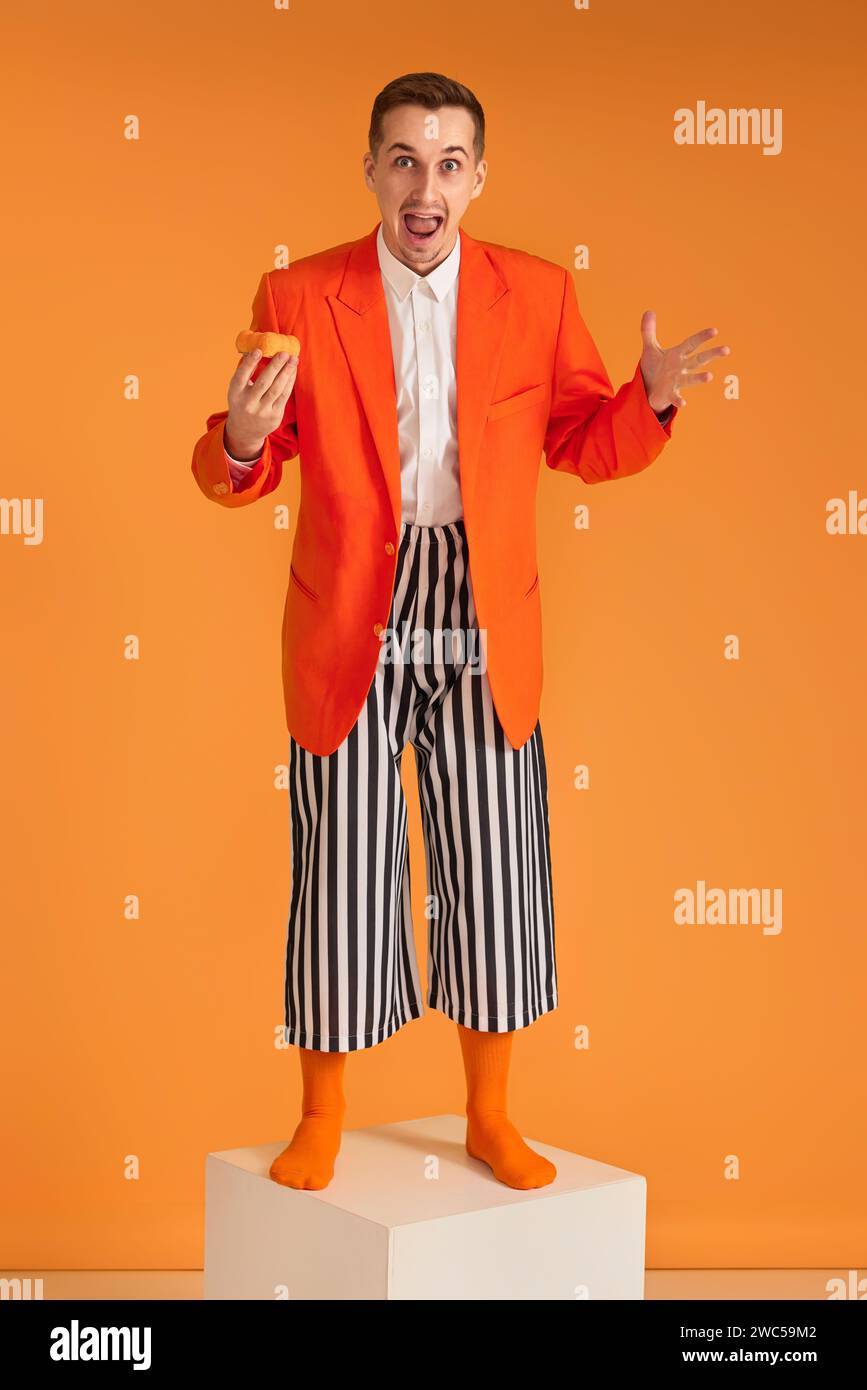 extravagant funny young man in orange jacket and striped pants on ...