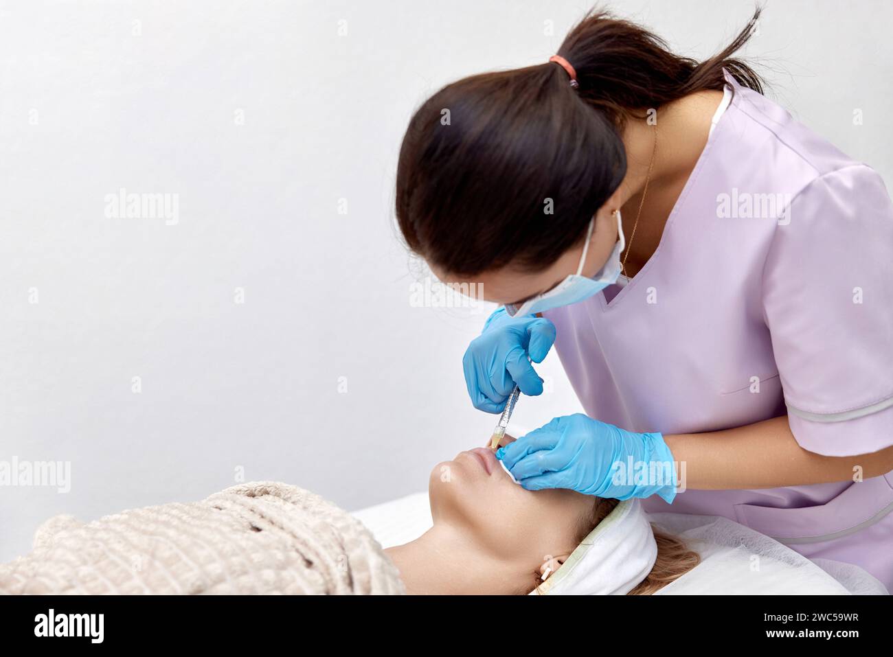 beautician makes injections to enlarge the lips of beautiful woman ...