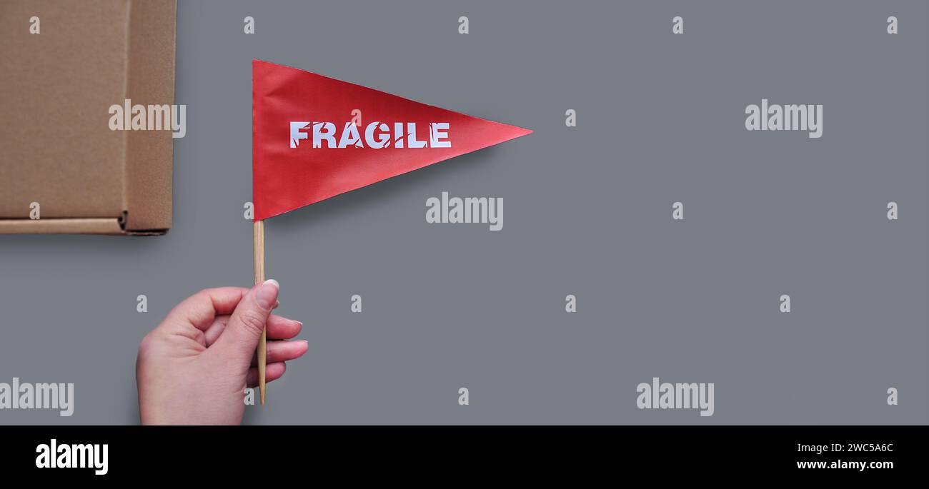 Small paper flags in hand with the warning 'Fragile' as a label. The ...
