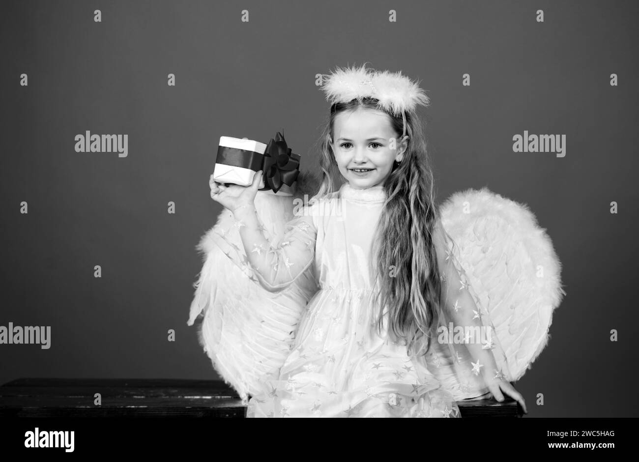 Kid girl angel with present gift, studio portrait. Little angel with ...