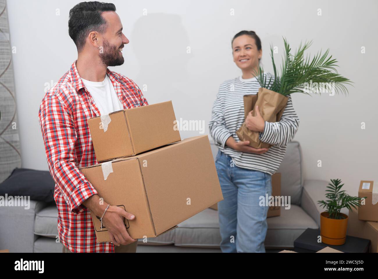 Positive woman and man carry boxes in new apartment Stock Photo - Alamy