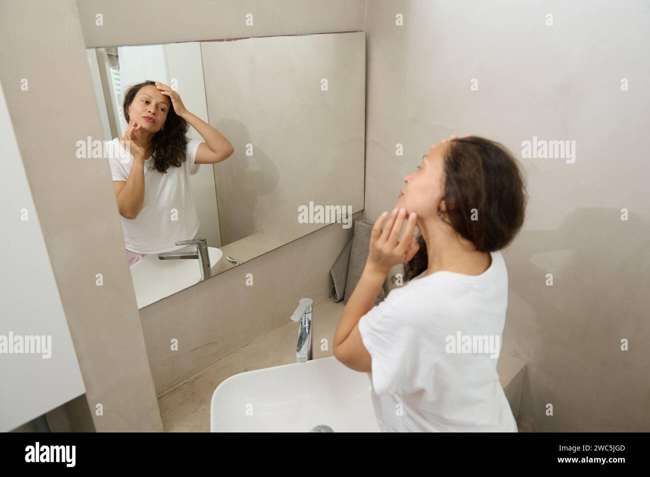 Happy pretty good looking young woman with curly brown hair, touching ...