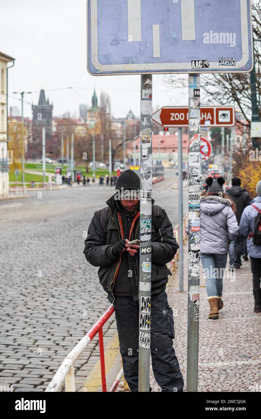 A homeless man with a phone on the street of the old historic medieval ...