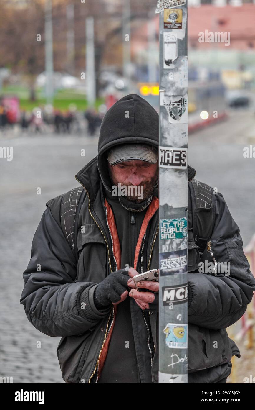 A homeless man with a phone on the street of the old historic medieval ...