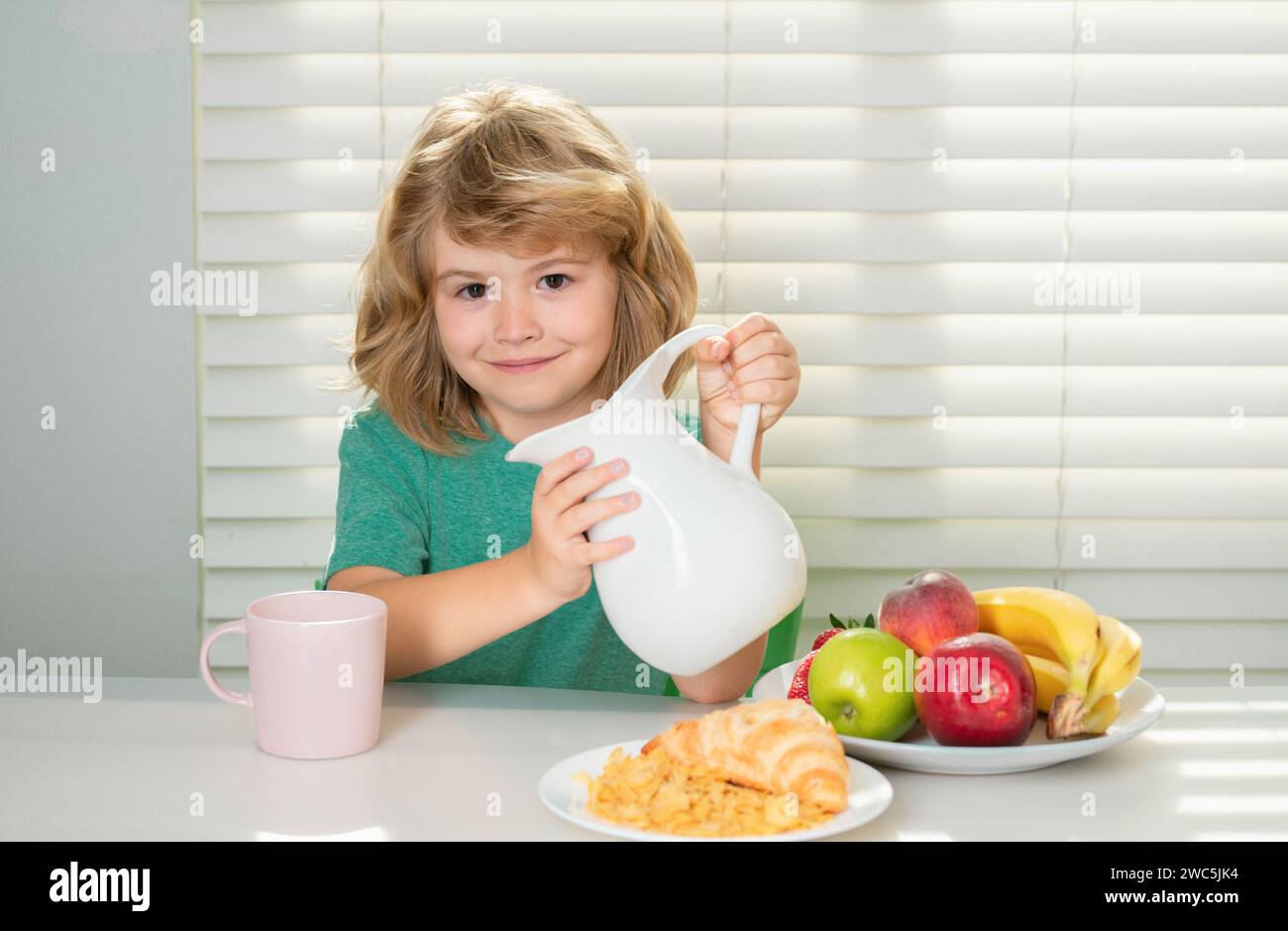 Fuuny little boy pouring whole cows milk for breakfast. Funny blonde ...
