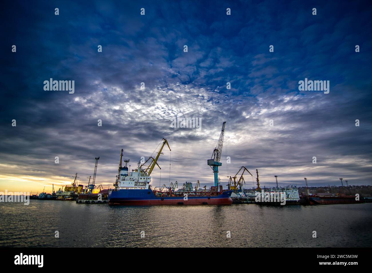Cargo ship docked at industrial port, cranes ready for unloading. Shipping containers, maritime ...