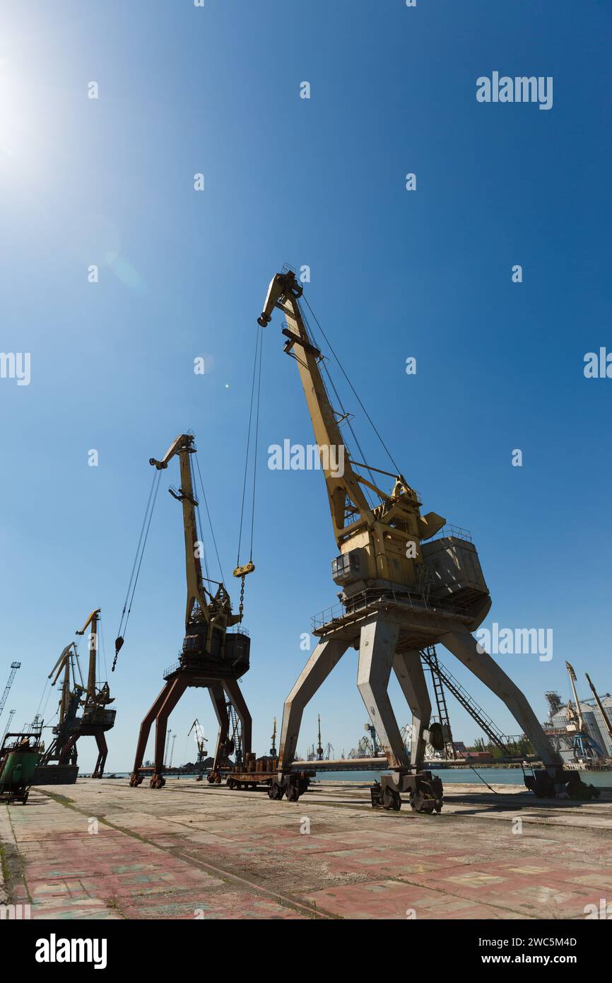 Decommissioned port cranes tower over abandoned dockyard under blue sky ... Decommissioned port cranes tower over abandoned dockyard under blue sky ...