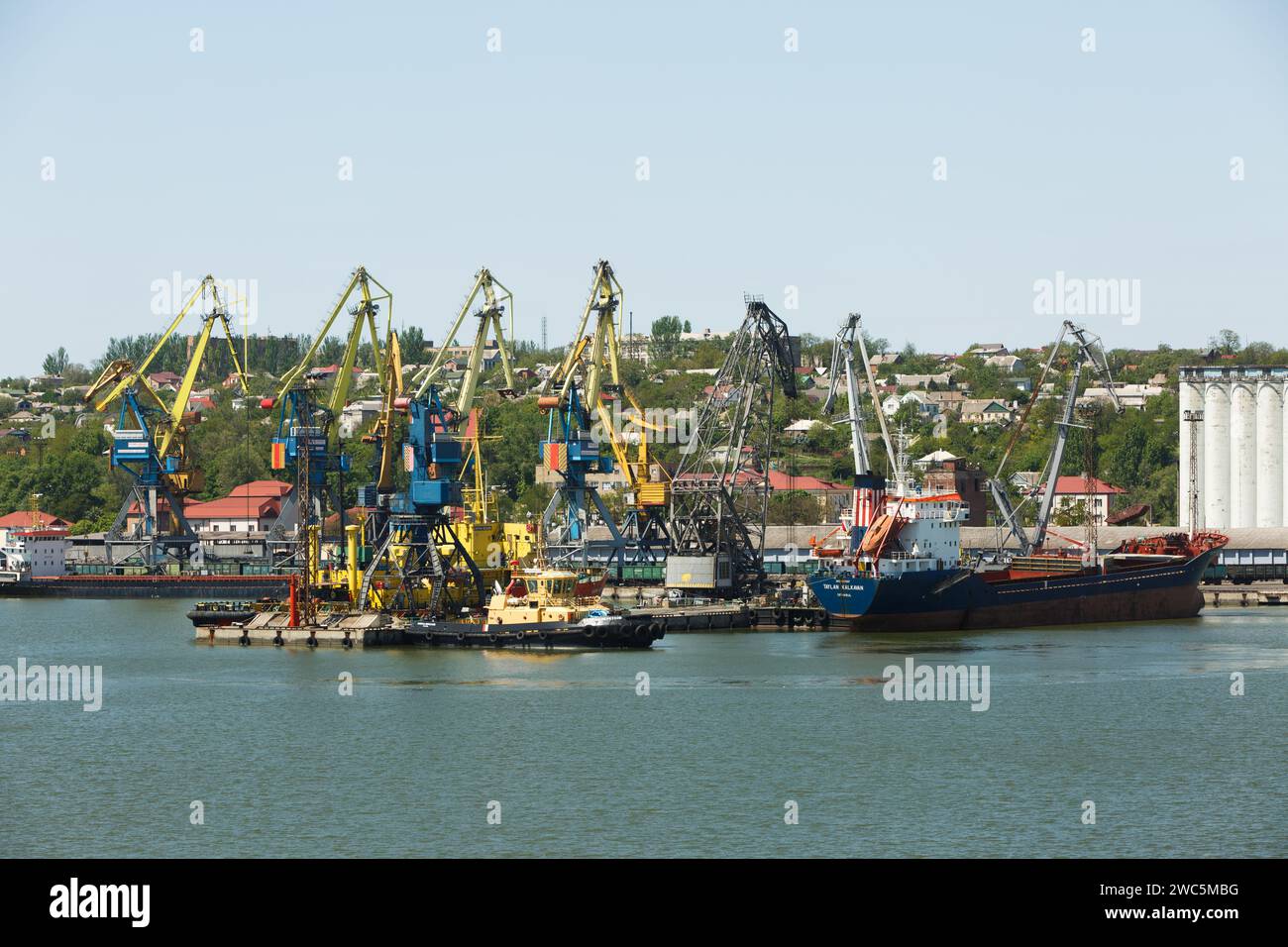 Cargo ship docked at industrial port with cranes. Freight vessel ...