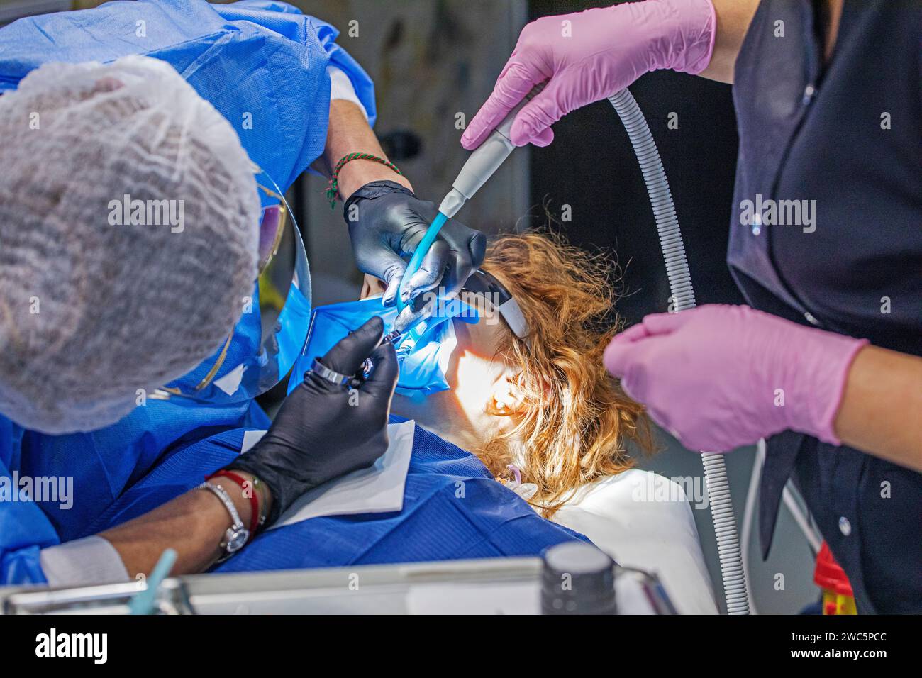 dentist treating a sick tooth to a patient together with an assistant ...