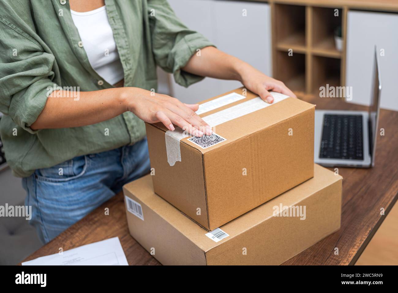 Woman hand apply QR code sticker to parcel, showcasing online shopping ...
