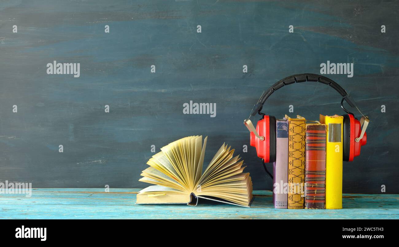 audio book concept, with stack of books, vintage headphones and an open ...