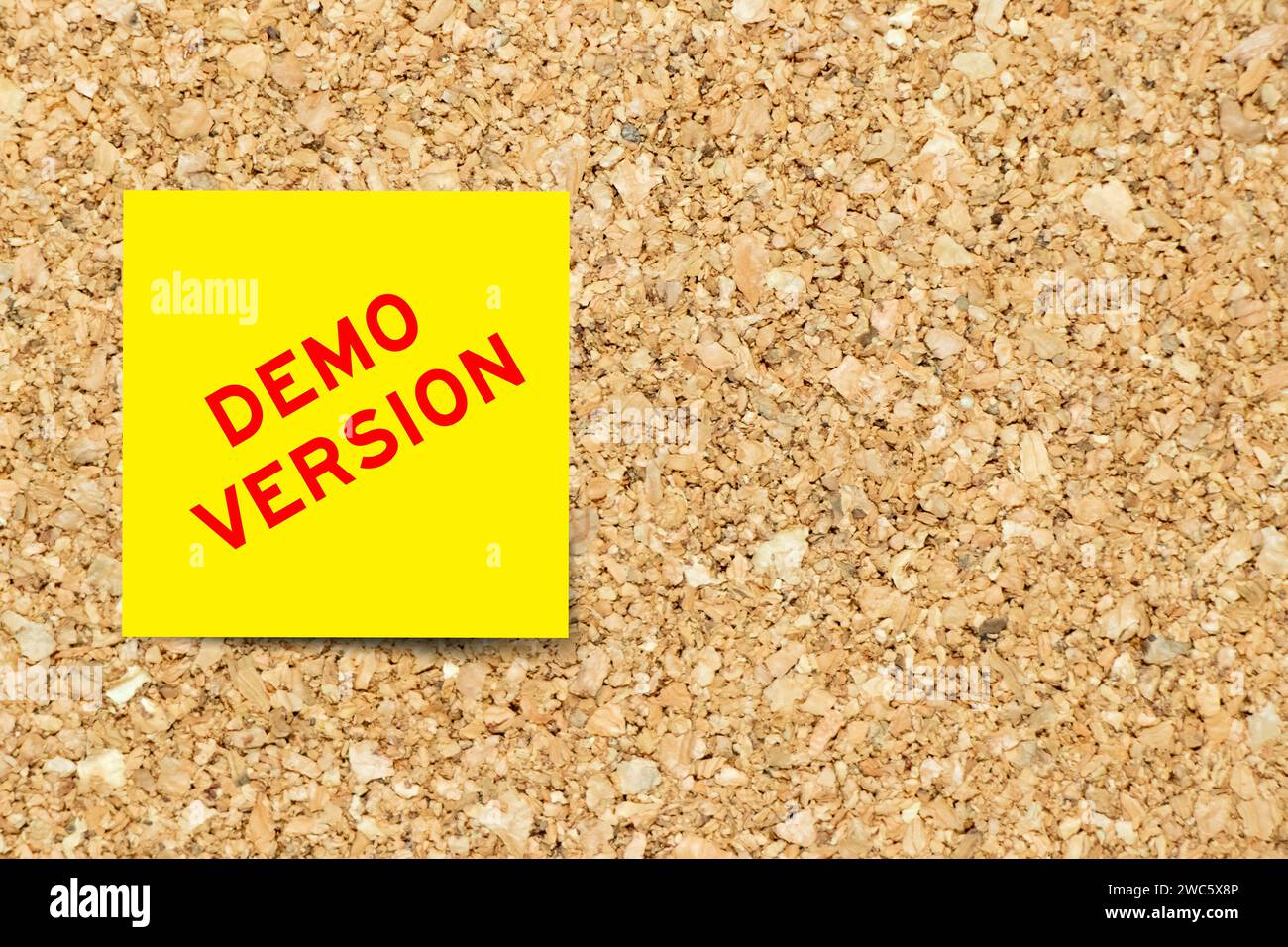 Yellow note paper with word demo version on cork board background with ...