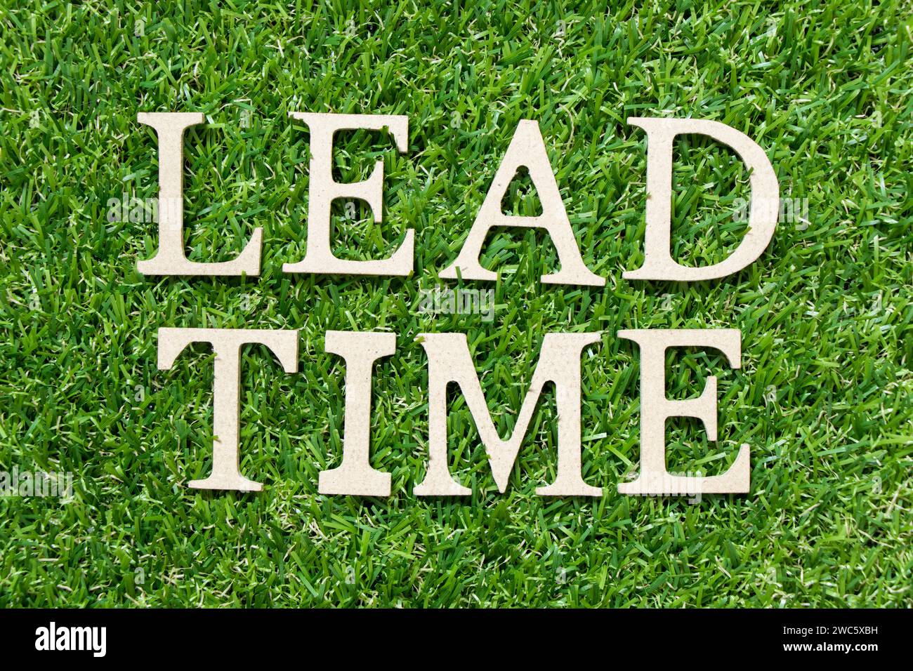 Wood letter in word lead time on green grass background Stock Photo - Alamy