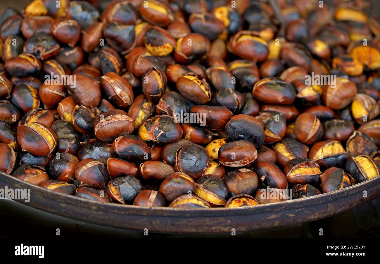 Fried chestnuts in a pan on a wooden stand, flat lay. Fresh roasted chestnuts for christmas or ...