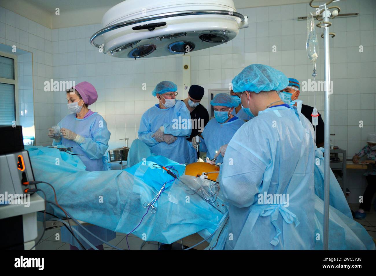 Laparoscopy surgery. Surgeons in face masks standing around patient ...