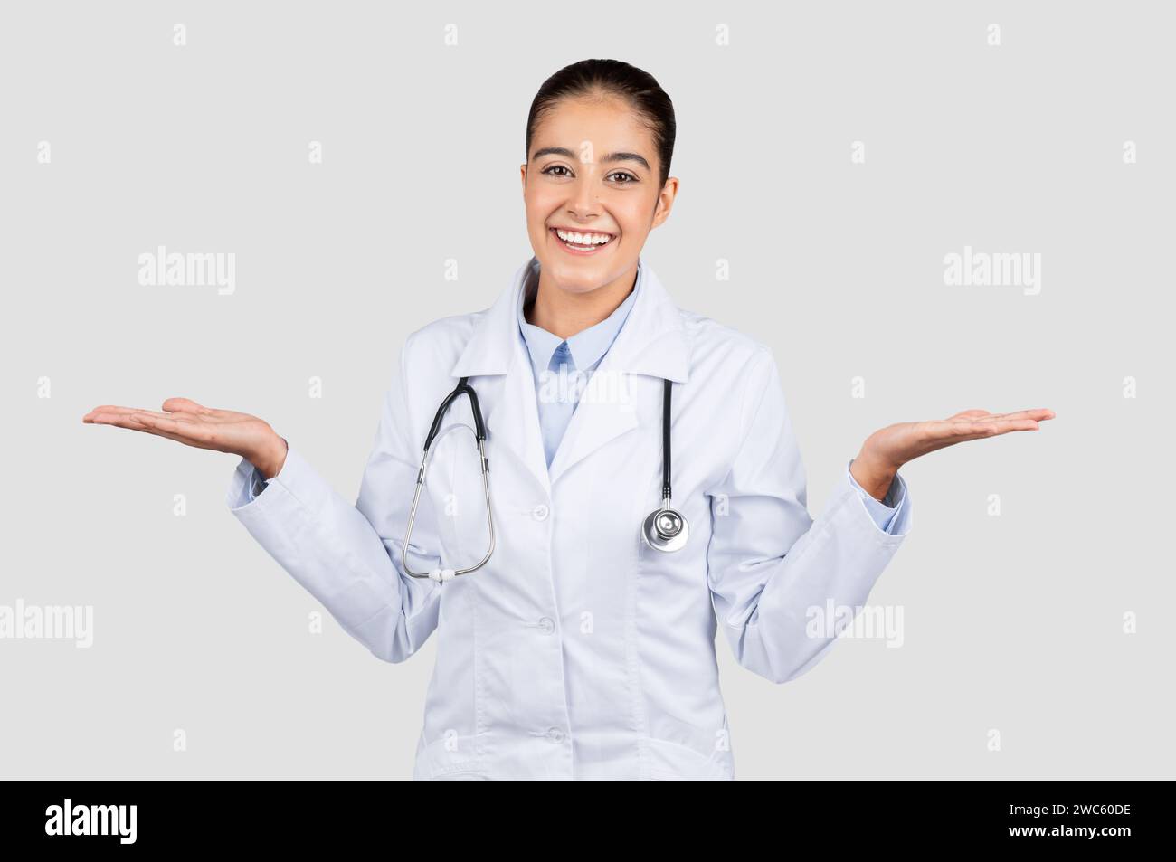 A joyful female doctor with a stethoscope joyfully shrugs with open ...