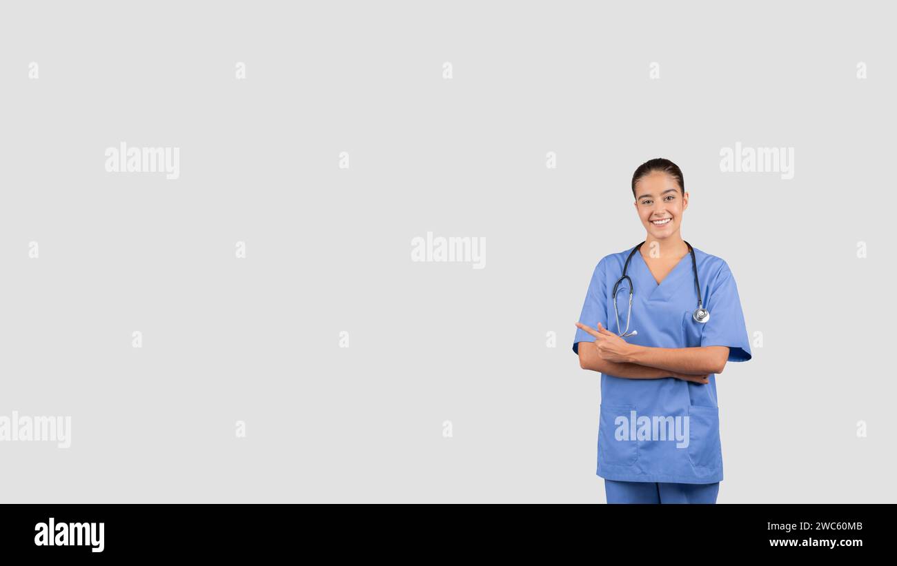 Cheerful european nurse in blue scrubs with crossed arms and a ...