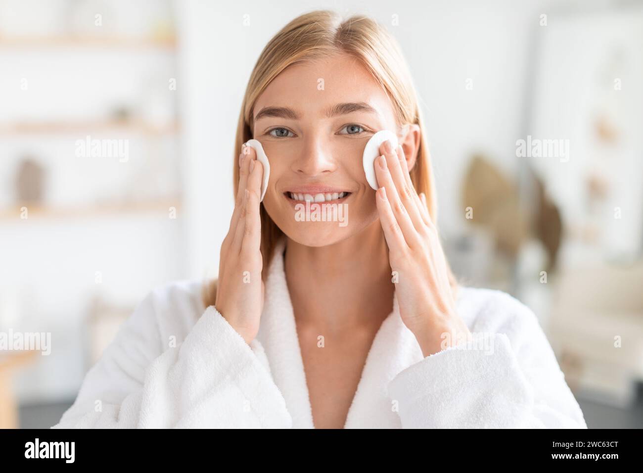 Young blonde woman pressing cotton pads to her cheeks indoor Stock ...
