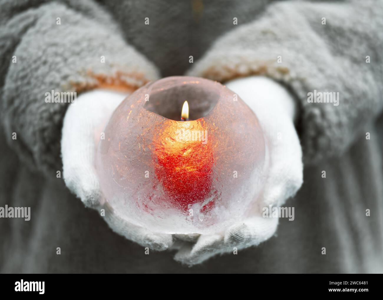 Handmade ice globe lantern with red candle burning in the girls hands ...