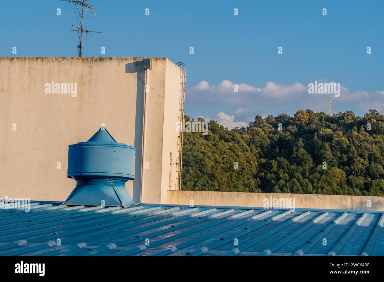 Round cone shaped exhaust vent on top of blue metal roof in front of ...