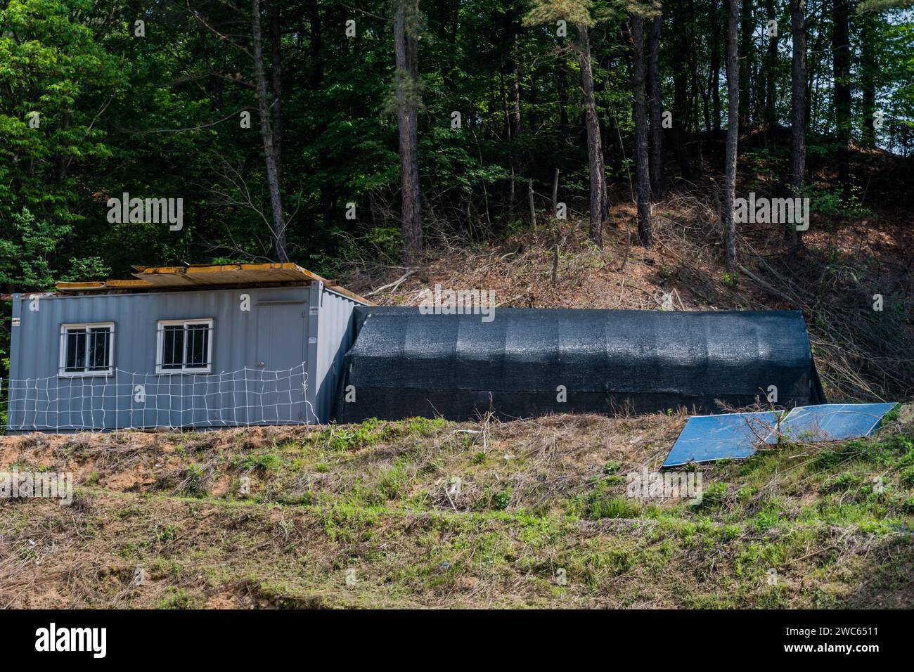 Two storage buildings on hillside in wooded farm region, one metal and ...
