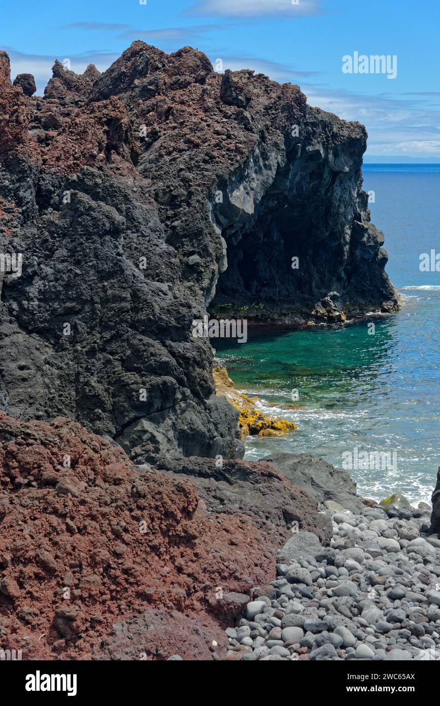 Rugged coastline with steep volcanic cliffs jutting out into the deep ...