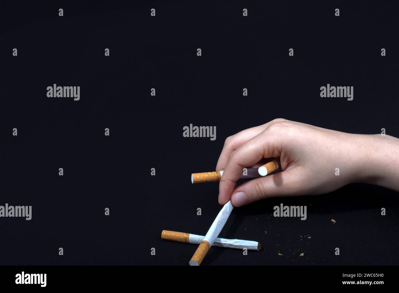 Hand is holding crossed cigarettes on black background Stock Photo - Alamy