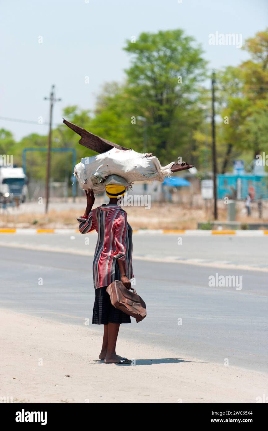African woman carrying scrap metal on her head through the streets ...