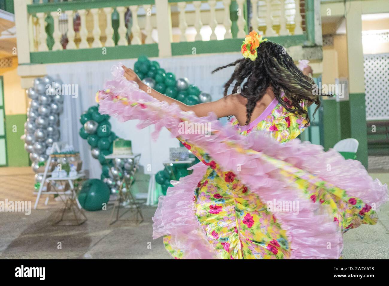 Exuberant female dancer twirling in a floral cumbia dress at a cultural ...