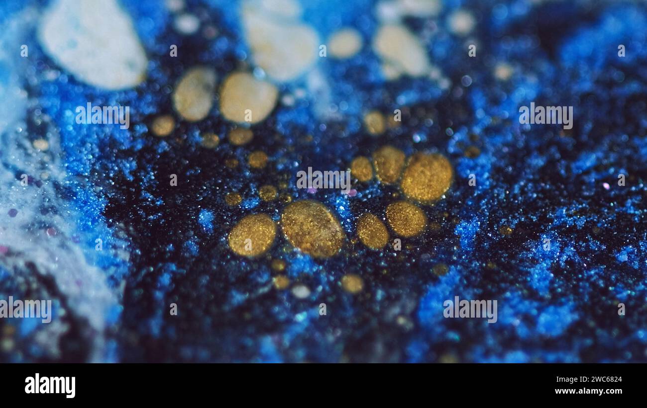 Sparkling paint flow glitter oil drops blue golden Stock Photo - Alamy