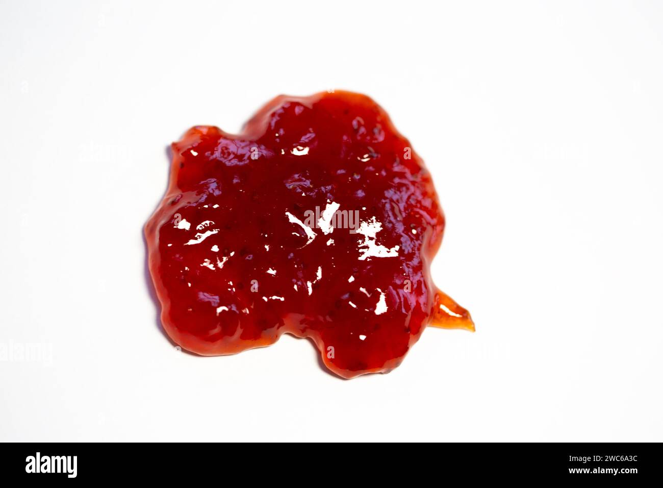 A spoonful of strawberry jam dropped onto a white background Stock ...
