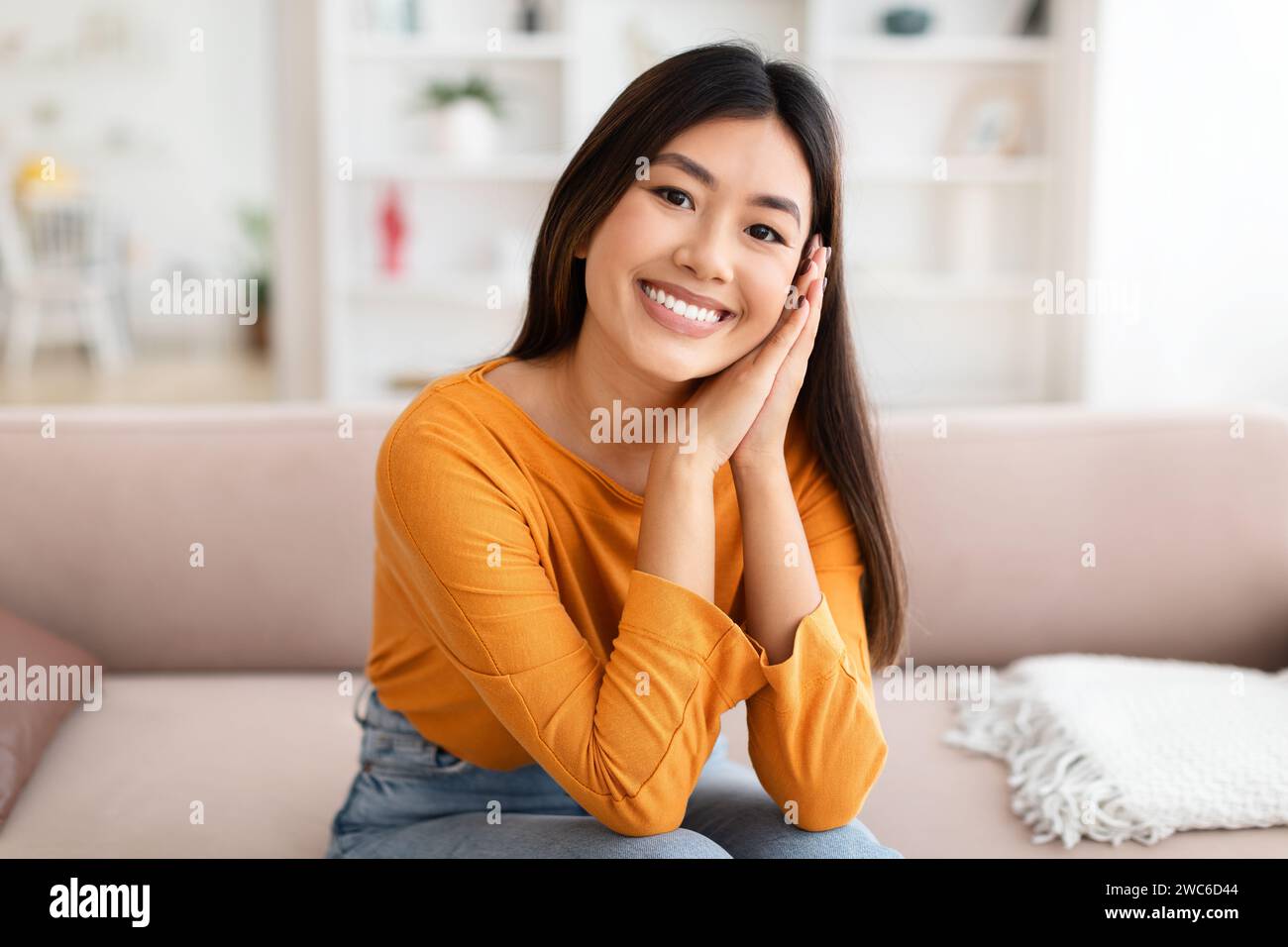 Cute pretty chinese lady sitting on couch at home Stock Photo - Alamy