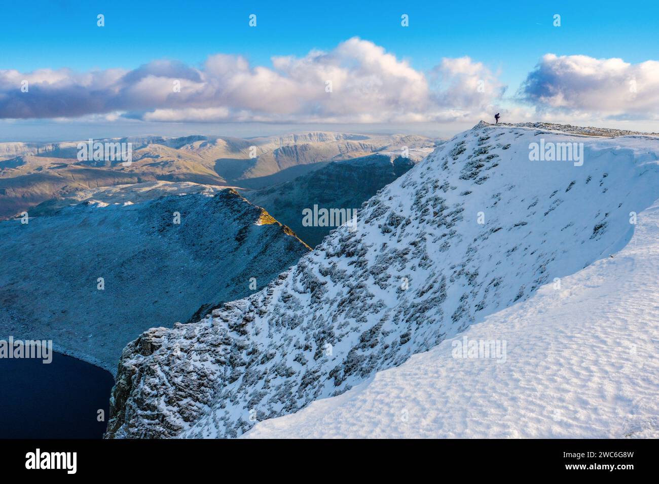 A hill walker on the summit of Helvellyn in winter. Lake District ...