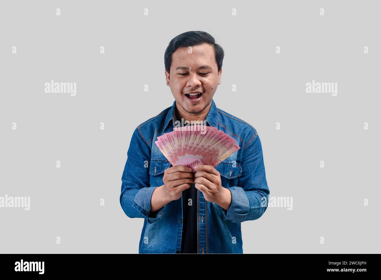Young Asian man holding money showing happy expression when looking to ...