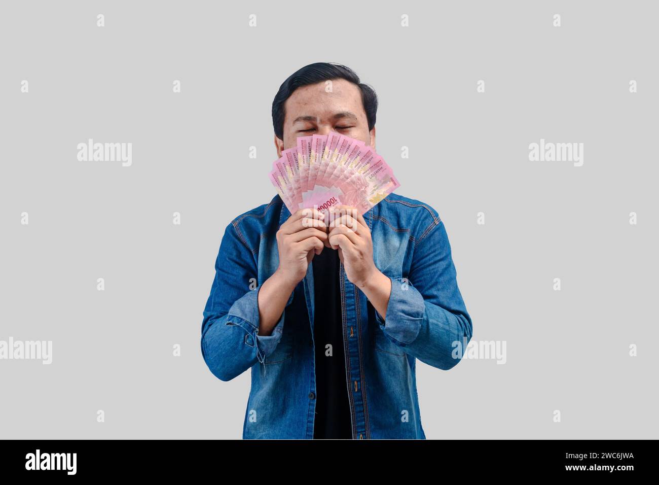 Young Asian man holding money showing happy expression when smell to ...