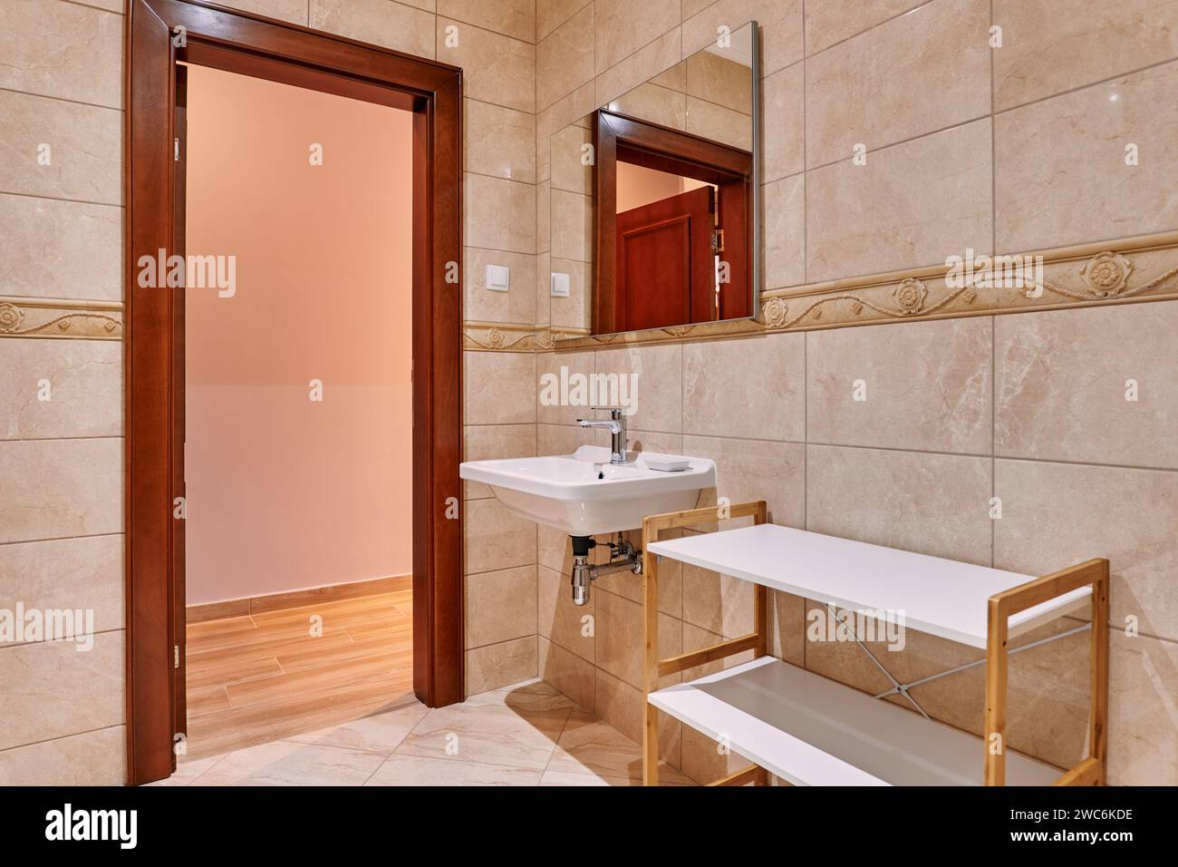 Sink with faucet at the entrance to the bathroom next to the linen rack ...