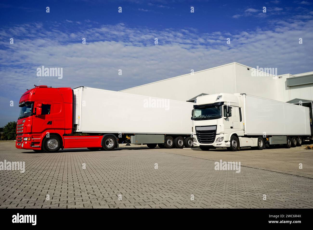 Transportbranche - roter und weißer LKW stehen vor einer Halle und ...