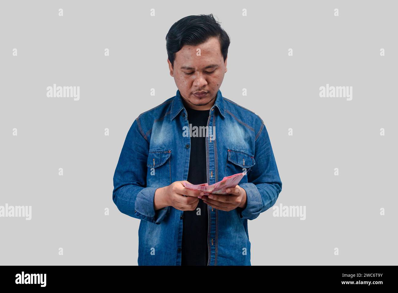 Young Asian man showing confused face expression while counting paper ...