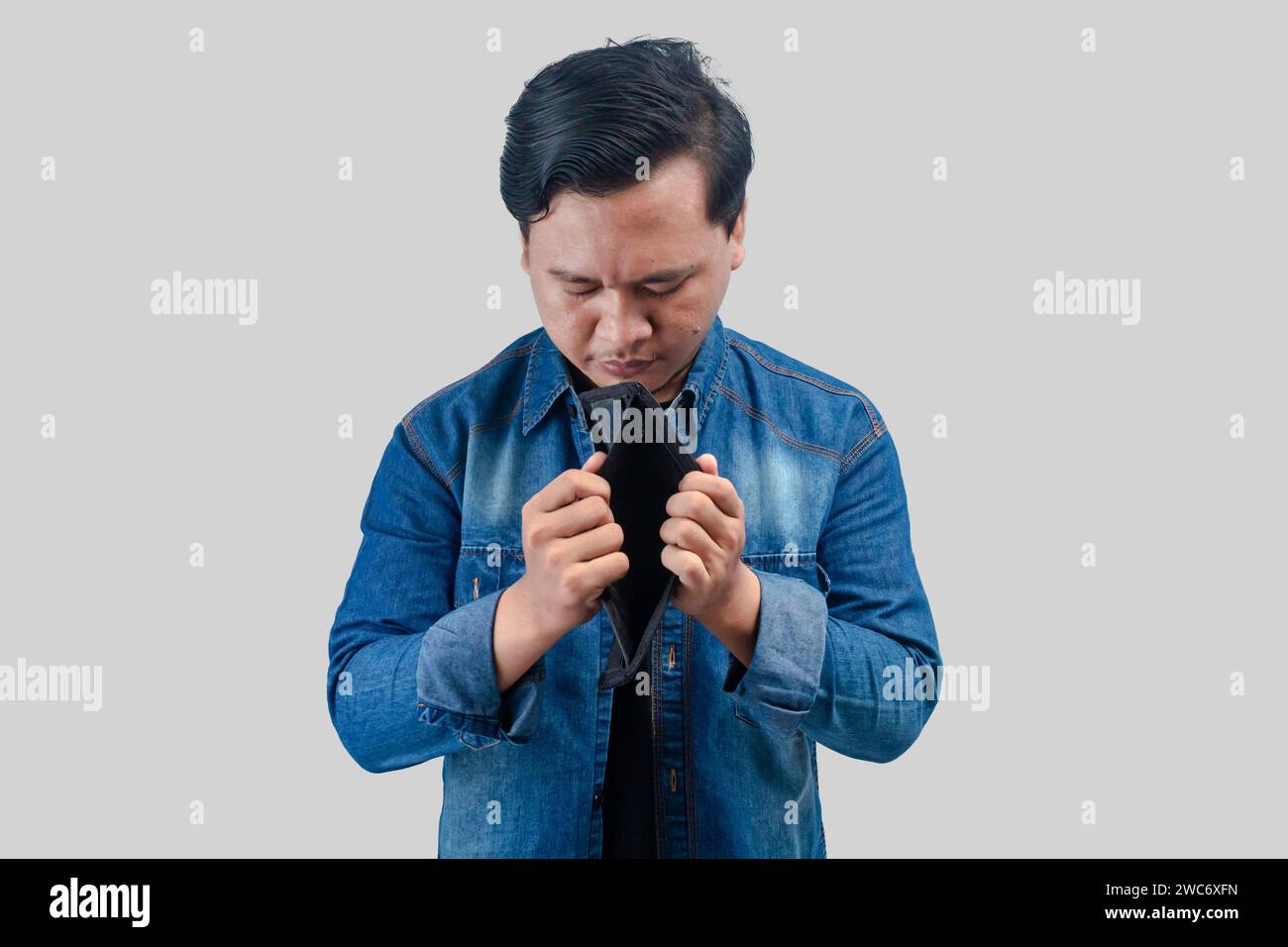 Young Asian man showing sad face expression while holding his empty ...