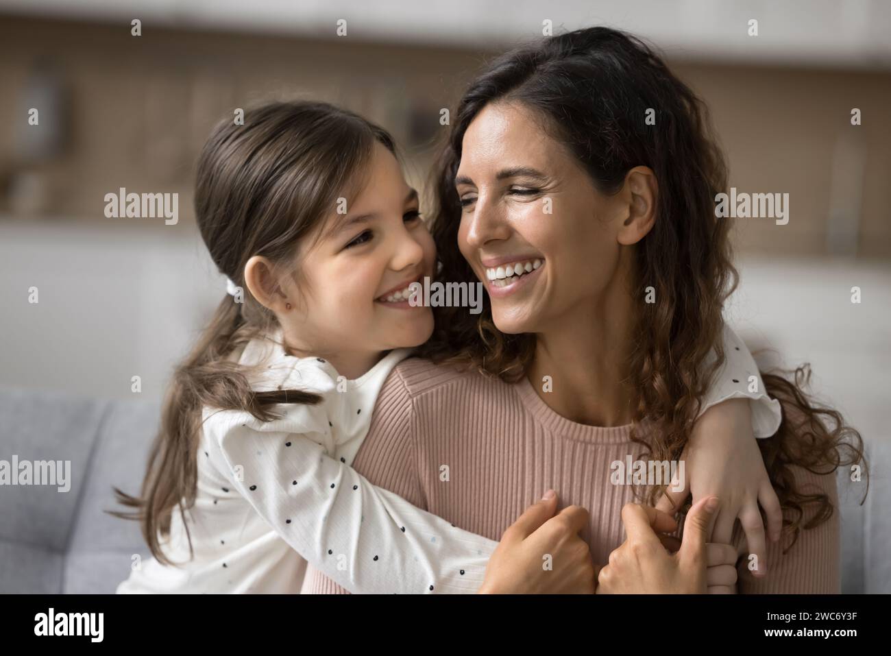 Cheerful mom and girl with white teeth hugging and laughing Stock Photo ...