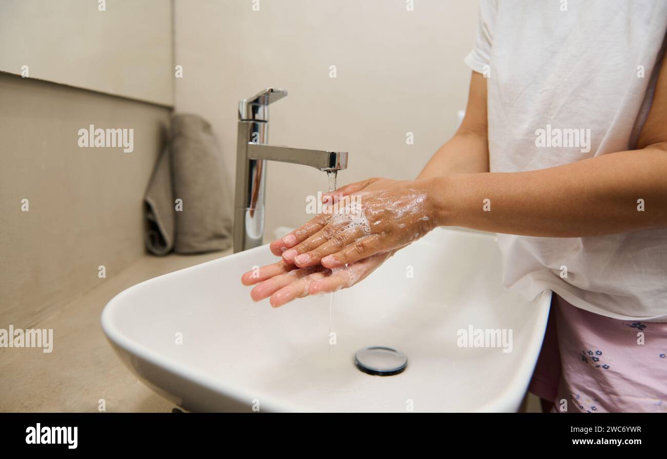 Close-up of a woman washing hands with soap, rubbing nails under the ...